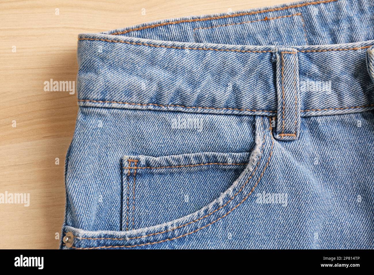 Stylish light blue jeans on wooden background, closeup of inset pocket ...