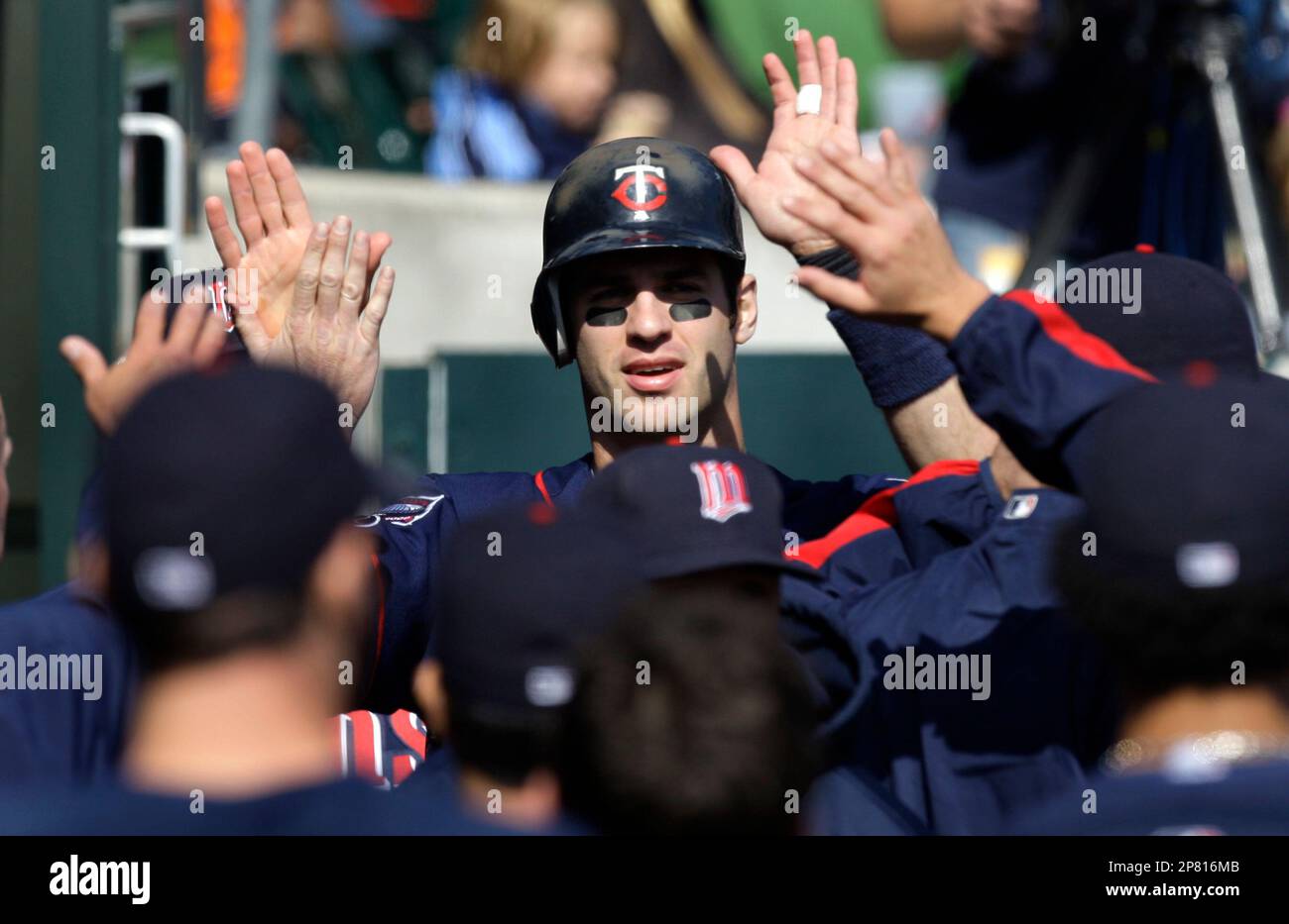 Minnesota Twins' Joe Mauer is congratulated in the dugout after scoring ...