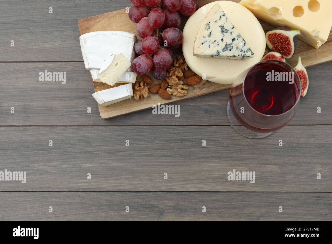 Different types of delicious cheeses, snacks and wine on wooden table ...