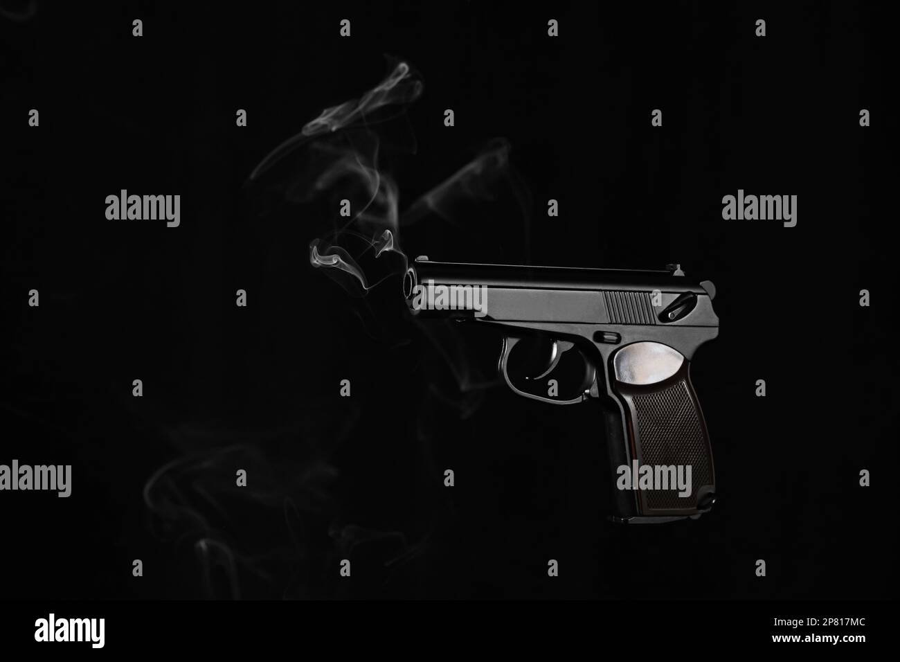 Handgun with smoke coming out of barrel on dark background, space for ...