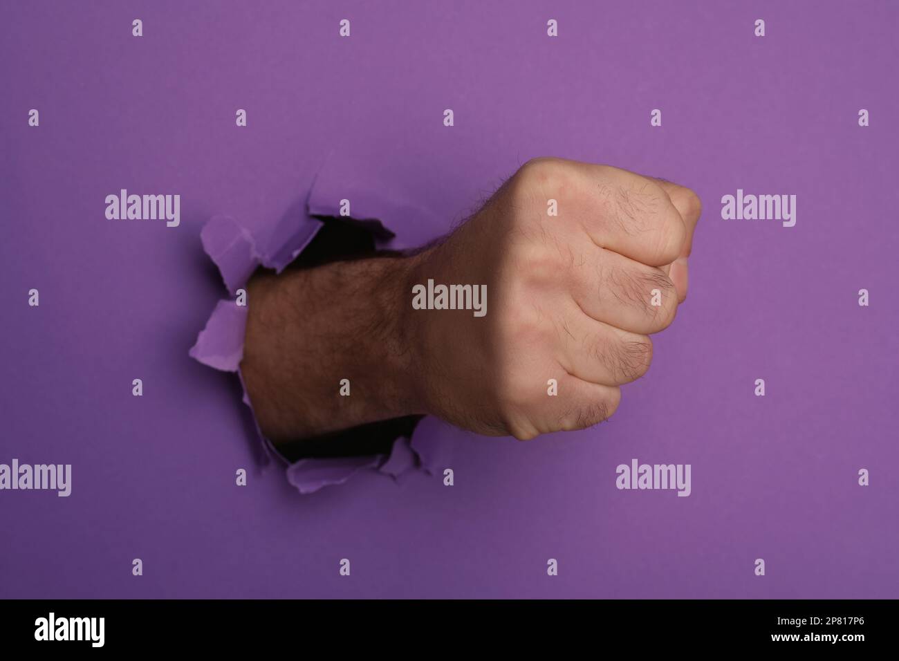 Man breaking through purple paper with fist, closeup Stock Photo - Alamy