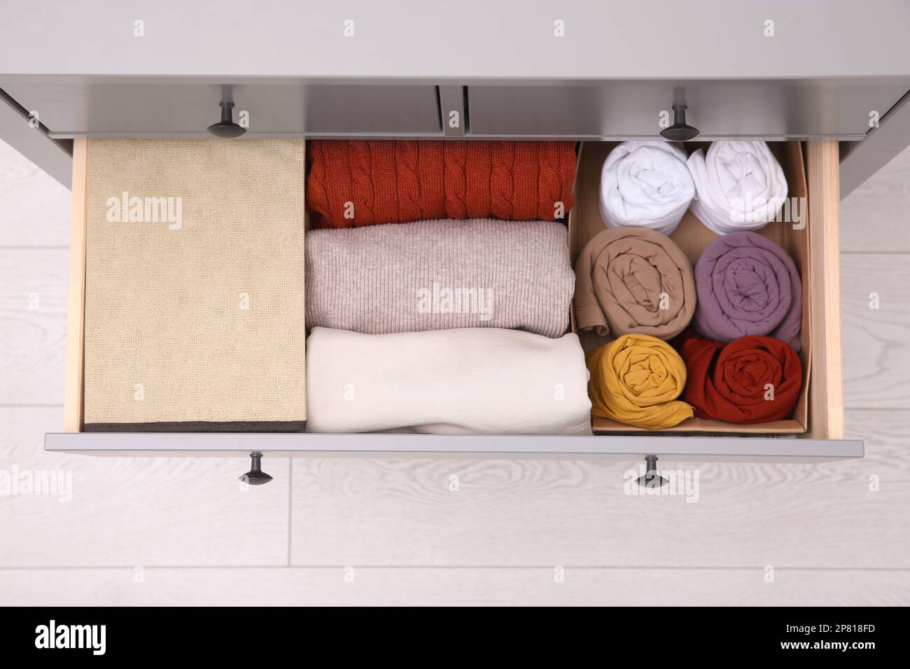 Open drawer with folded clothes indoors, top view. Vertical storage ...