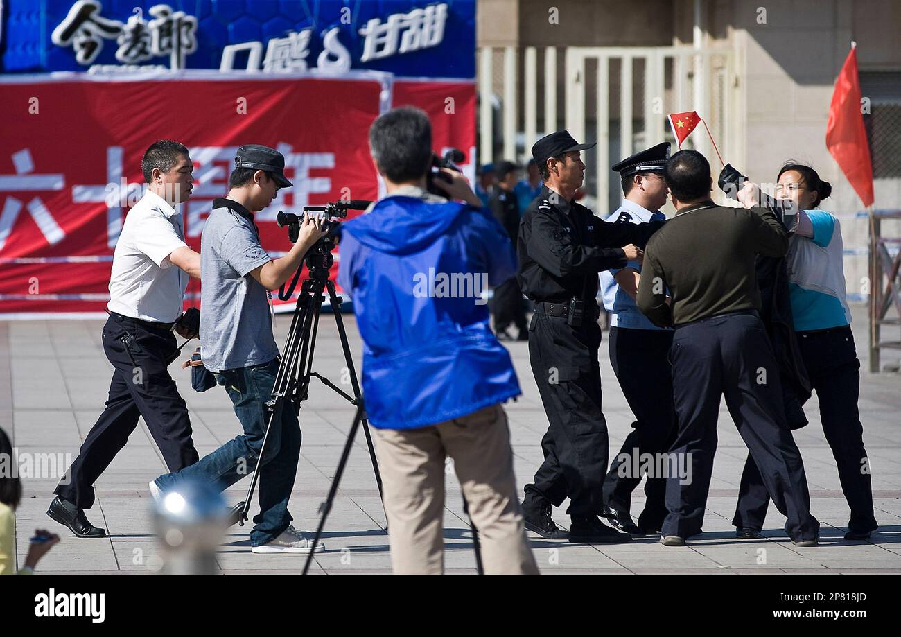A Chinese police officer, left, tries to stop a journalist to film the ...