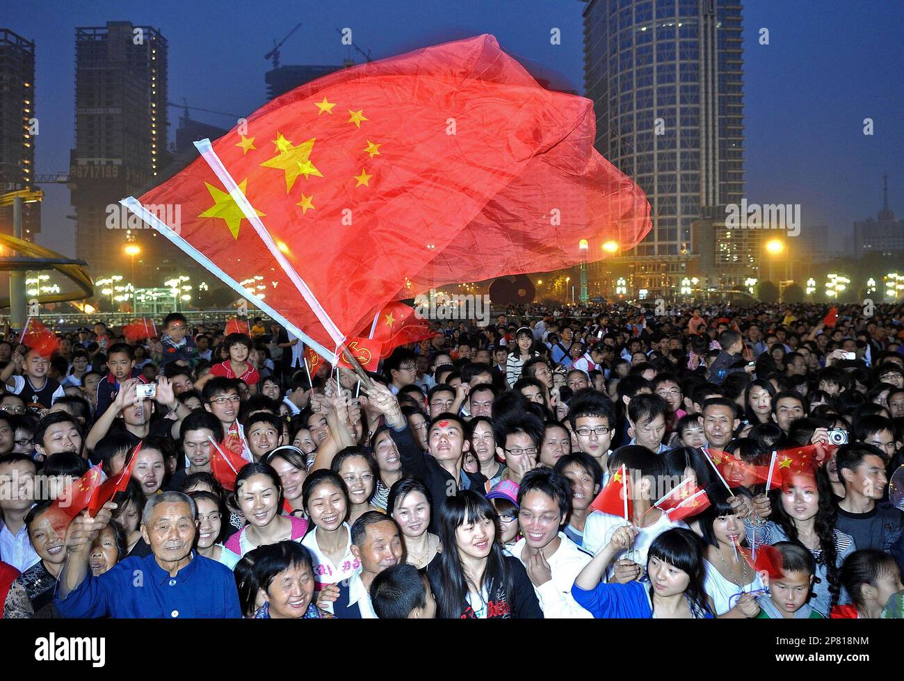 Local residents wave flags during a flag raising ceremony celebrating ...