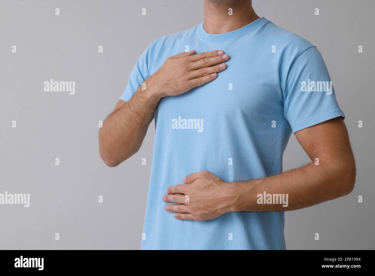 Man holding hands near chest on grey background, closeup. Space for ...
