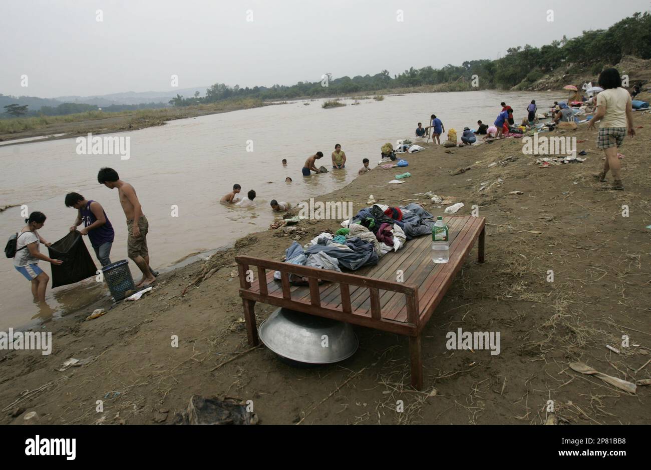 Flood victims wash their soiled belongings along a riverbank in ...