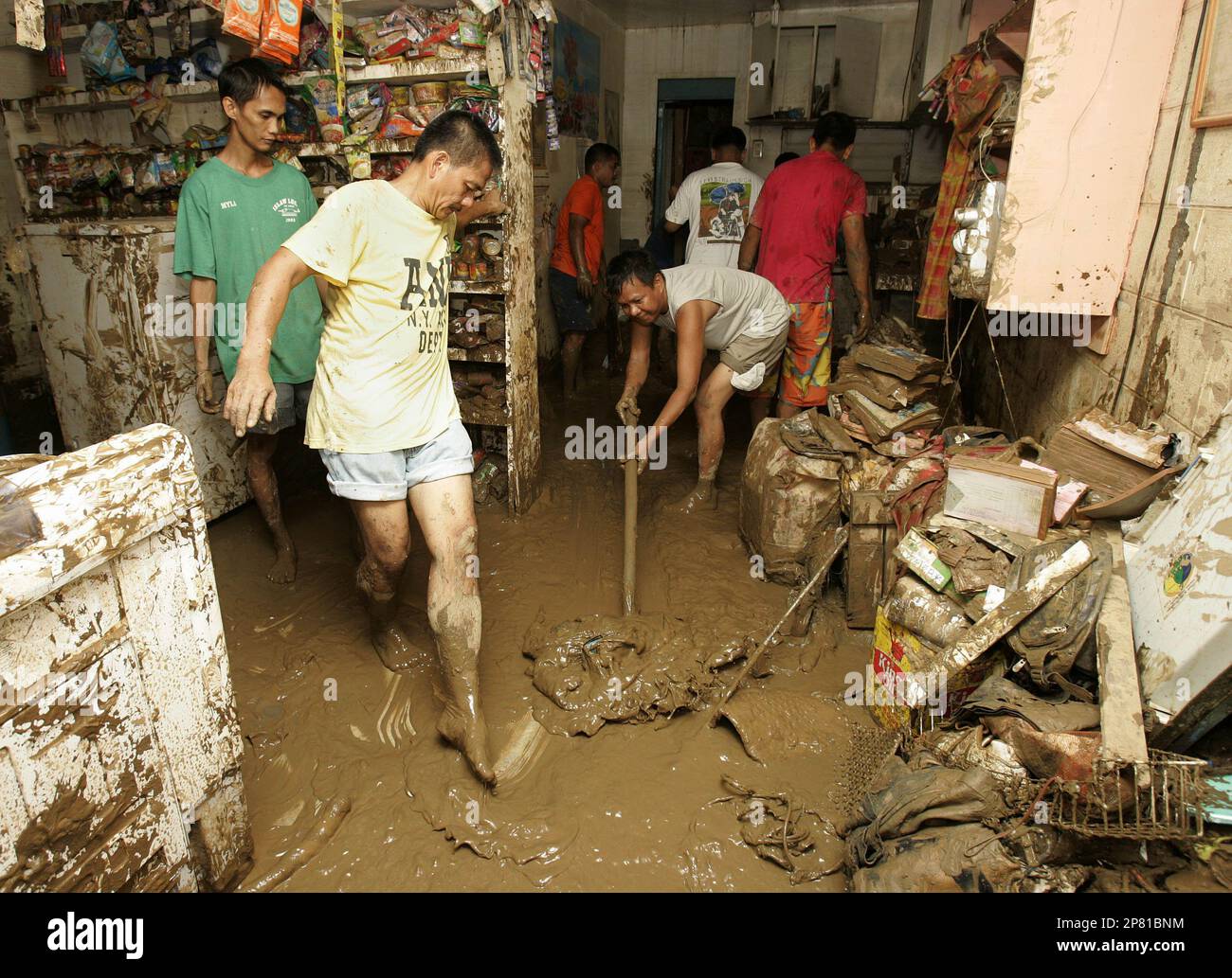 Filipino men try to clear out the mud inside a store in Rodriguez ...