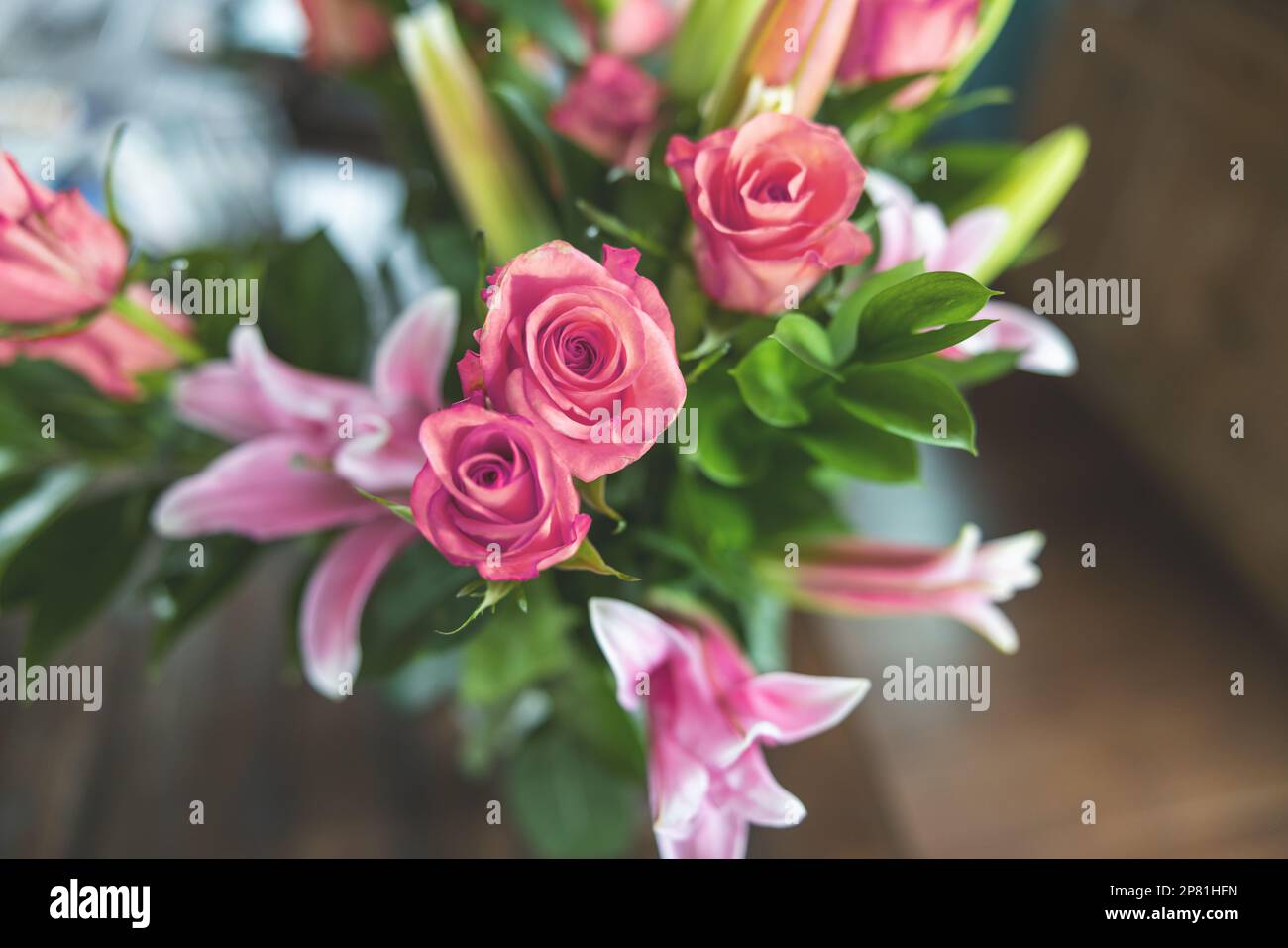A beautiful bouquet of pink and coral roses and lillies in a clear vase ...