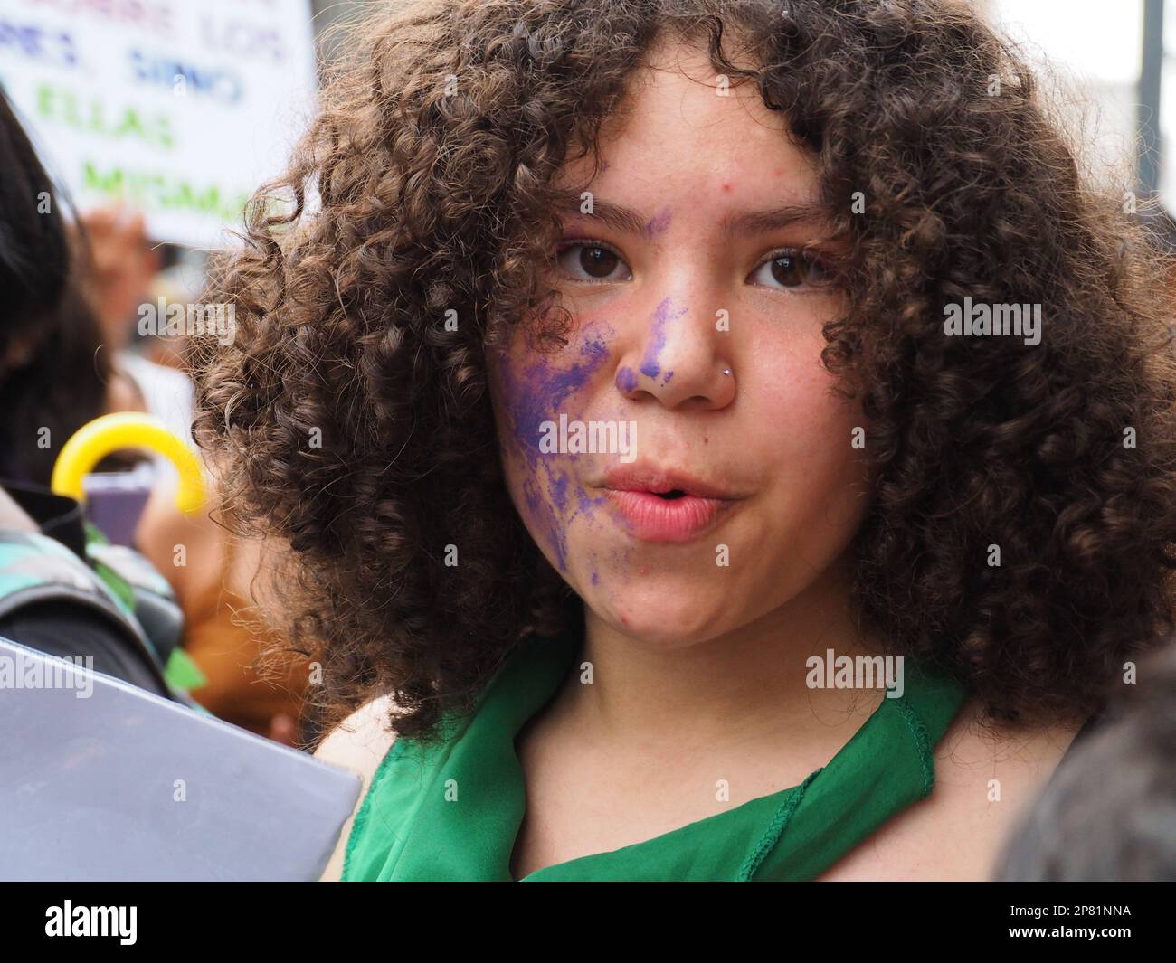 A young woman with her face stained with the purple color of feminism ...