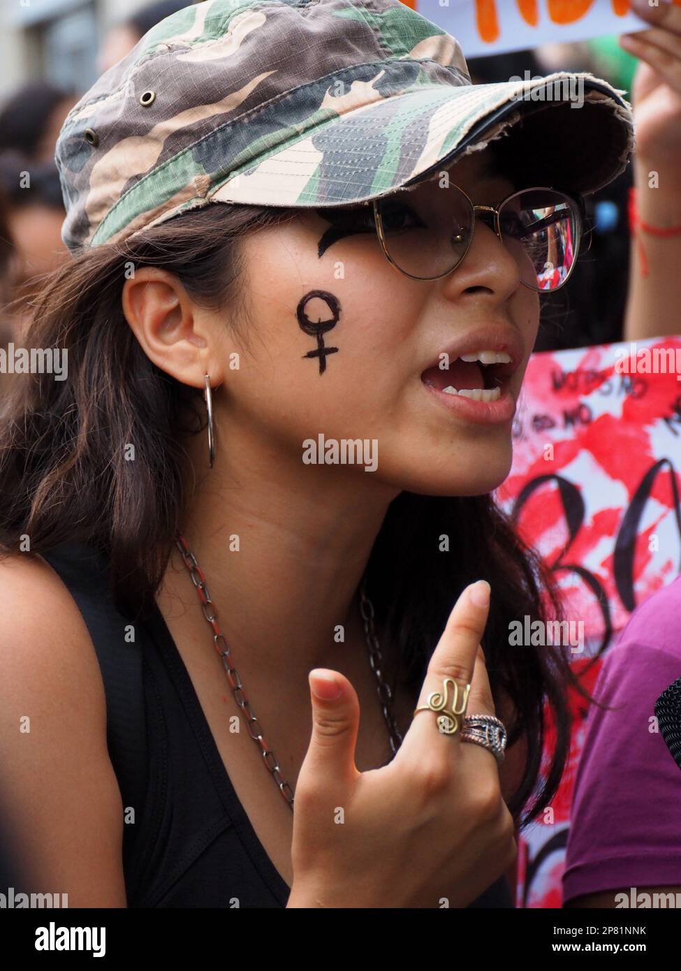 A woman with the feminist symbol painted on her face when dozens of ...