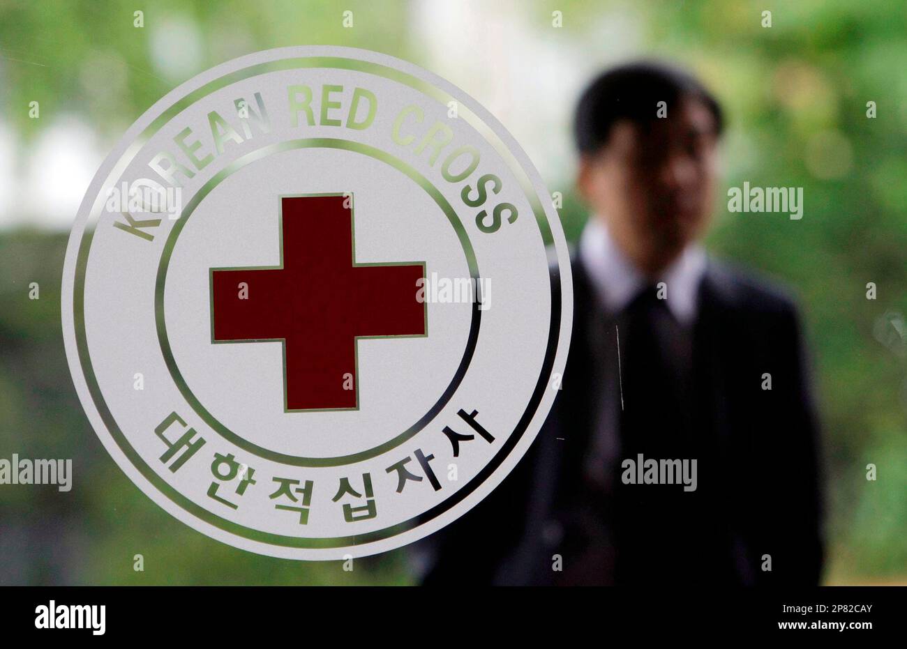 A South Korean man stands near the logo of the Korea Red Cross at its ...