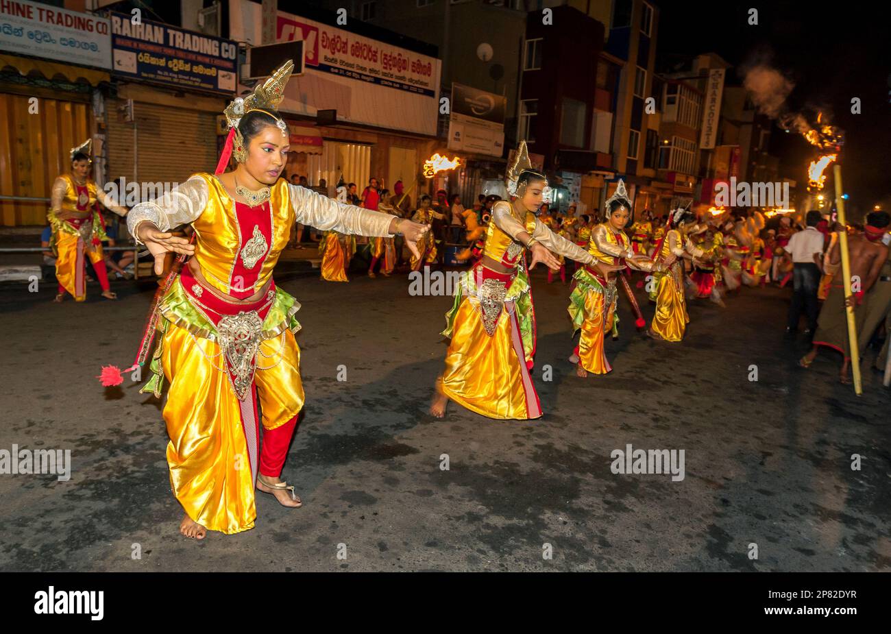 Colourfully dressed female performers parade along a street at Kandy in ...