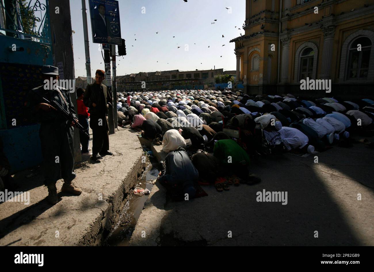 An Afghan police officer stands guards as Muslim Afghans offer Eid al ...