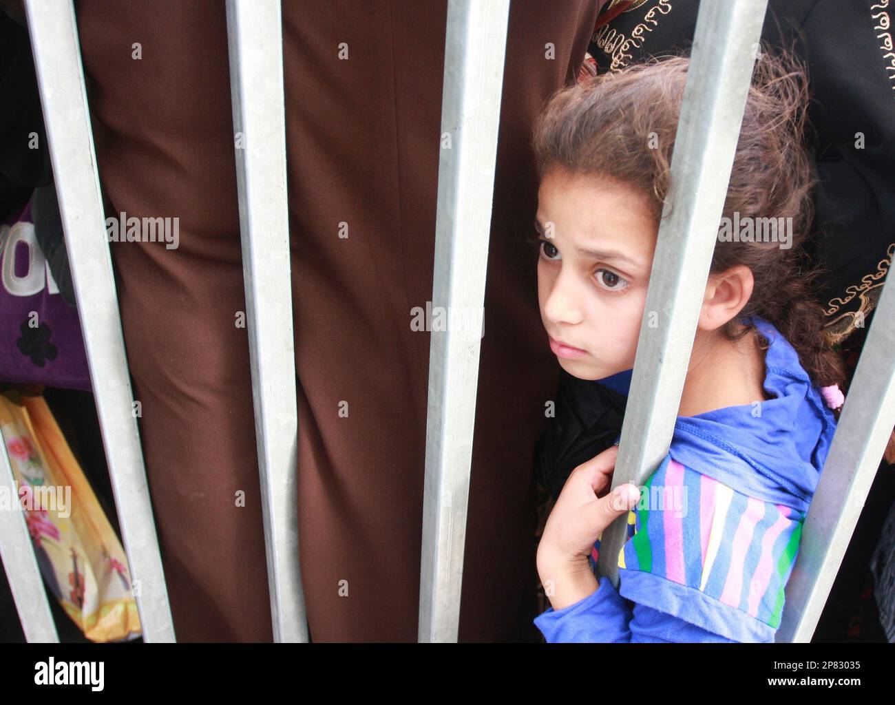 A Palestinian girl waits with her mother while trying to cross a ...