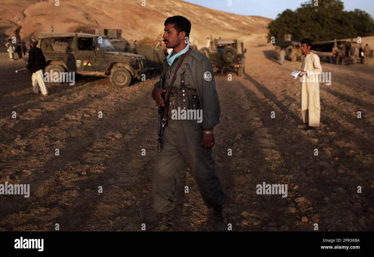 A Afghan police man secures the area as German ISAF soldiers prepare a ...