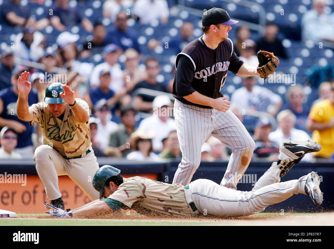 San Diego Padres' Adrian Gonzalez, bottom, slides into third base with ...