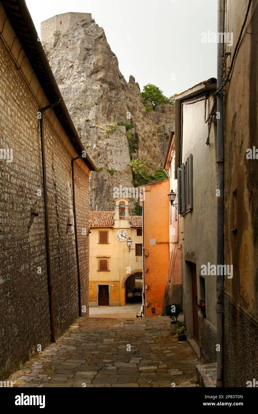 View down a medieval pathway of Roccalbegna to the tall of rock Pietra ...