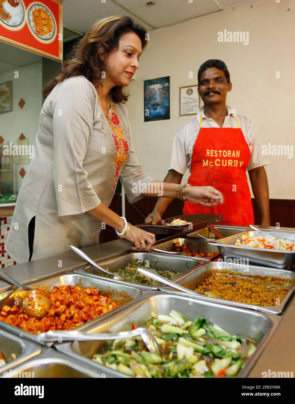 Wife of McCurry restaurant owner Kanageswary Suppiah, left, helps serve ...