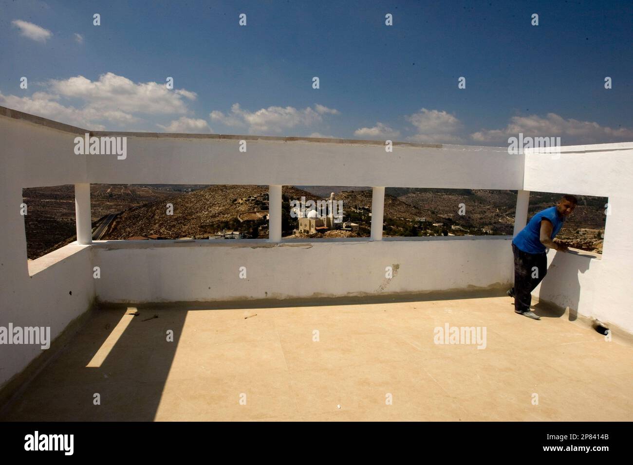 A Palestinian construction worker builds a new house in the Jewish West ...