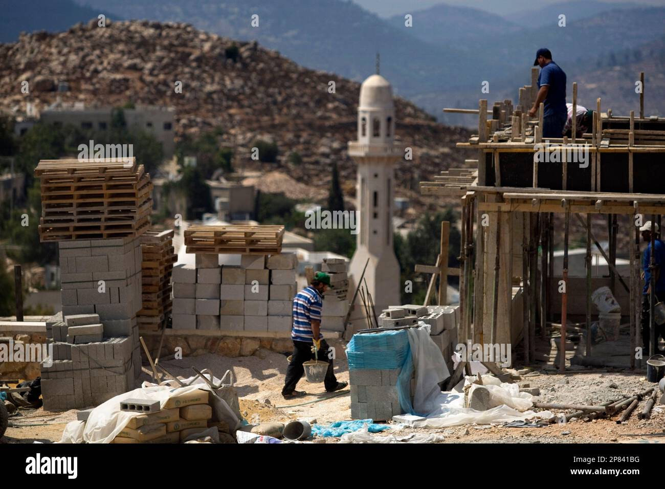 Palestinian construction workers build a new house in the Jewish West ...