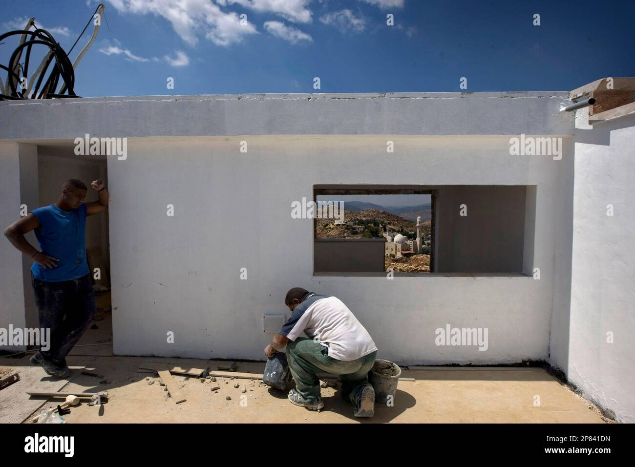 Palestinian construction workers build a new house in the Jewish West ...