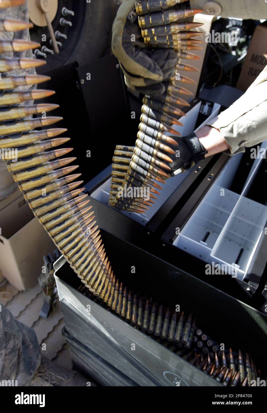 Soldiers with the 20th Special Forces Group load belts of ammunition as ...