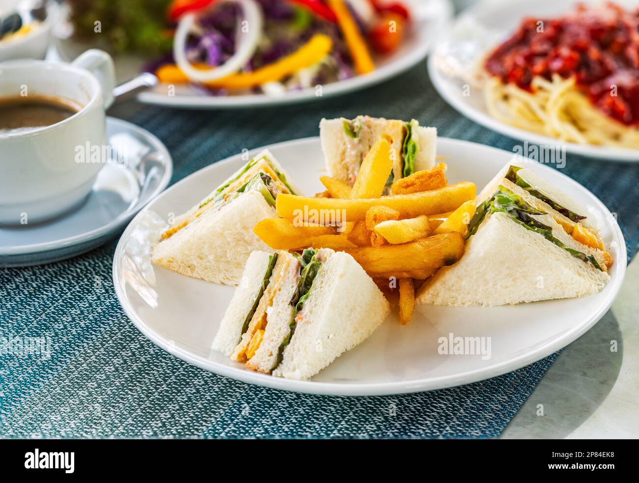 Breakfast, four sandwich clubs and french fried together on a white ...