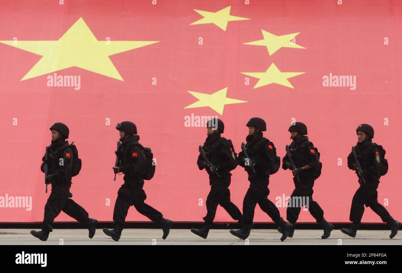 Armed paramilitary police officers run in front of a Chinese national ...