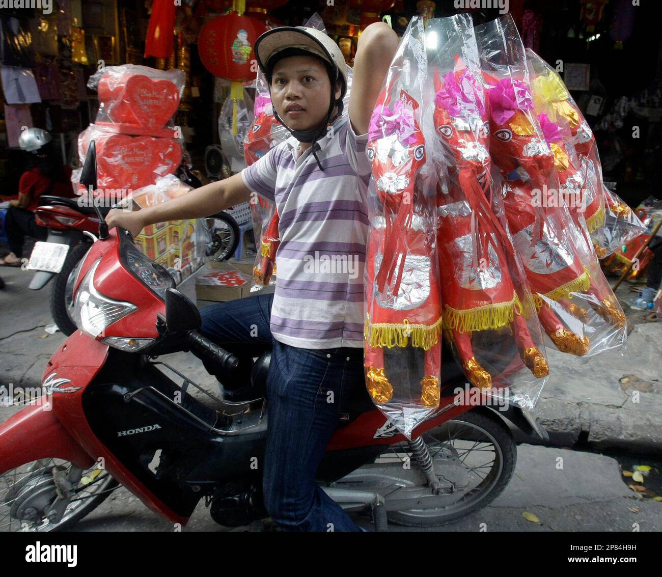 A man carries paper craft horses for Vu Lan Festival, known as the ...