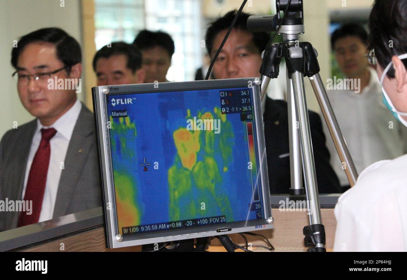 South Koreans pass by a thermal camera monitor showing the body ...