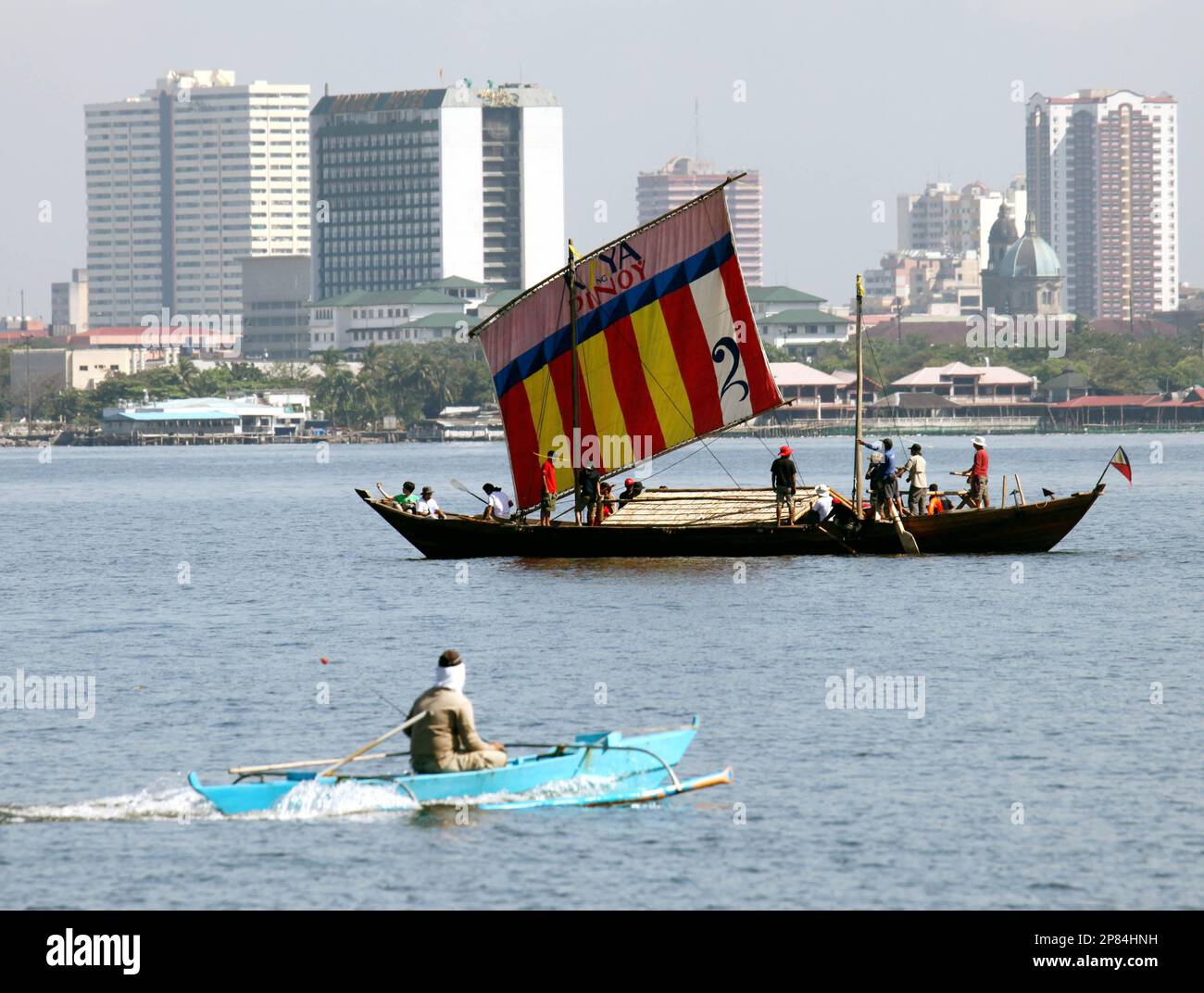 A boatman in a small outrigger, foreground, watches as Filipino ...