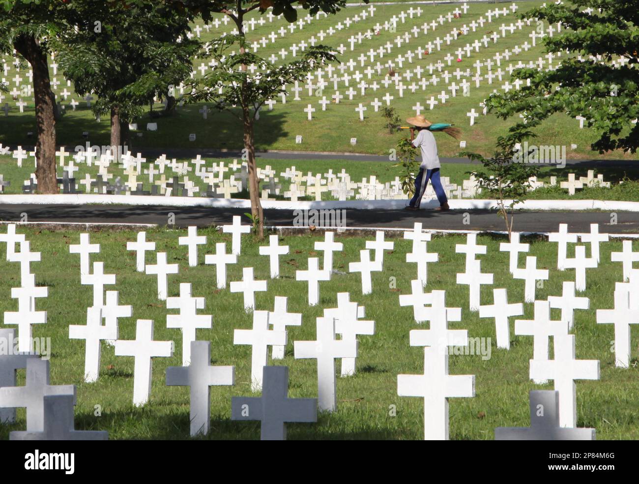 A Filipino cemetery worker prepares to clean crosses at the Heroes ...