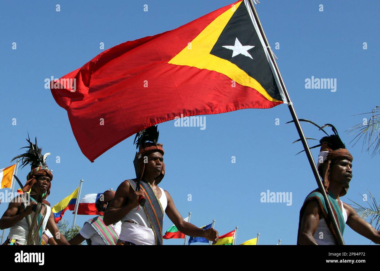 Timorese men in traditional dress carry East Timor national flag during ...