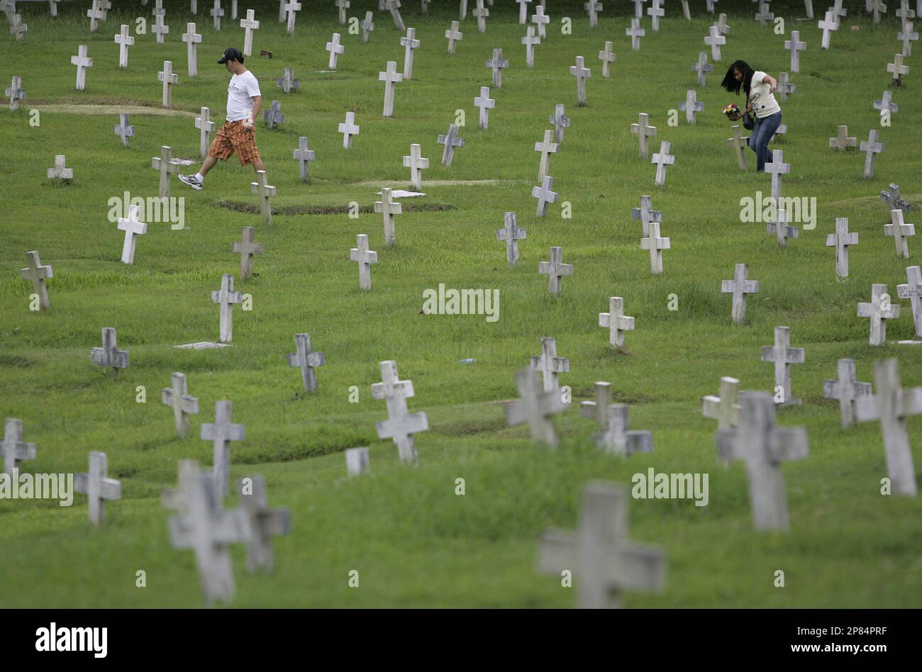 Two Filipinos walk across tombs at the Philippine Heroes Cemetery in ...