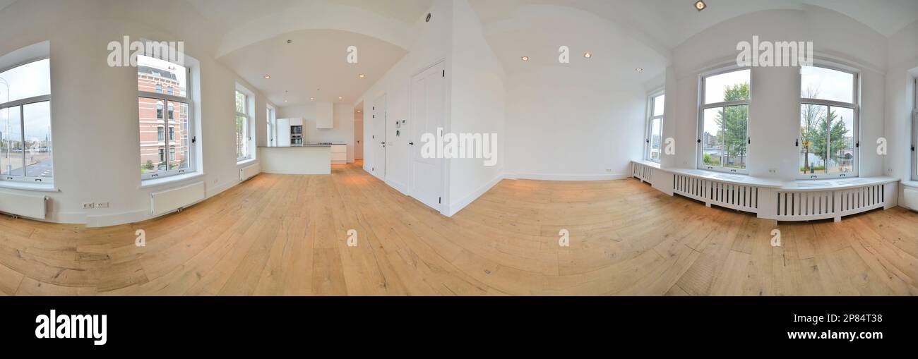 an empty living room with wood flooring and large windows looking out ...