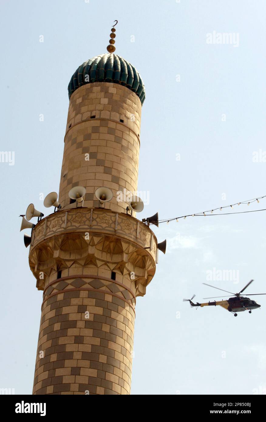 A helicopter flies past the minaret of a mosque in Baghdad, Iraq, where ...