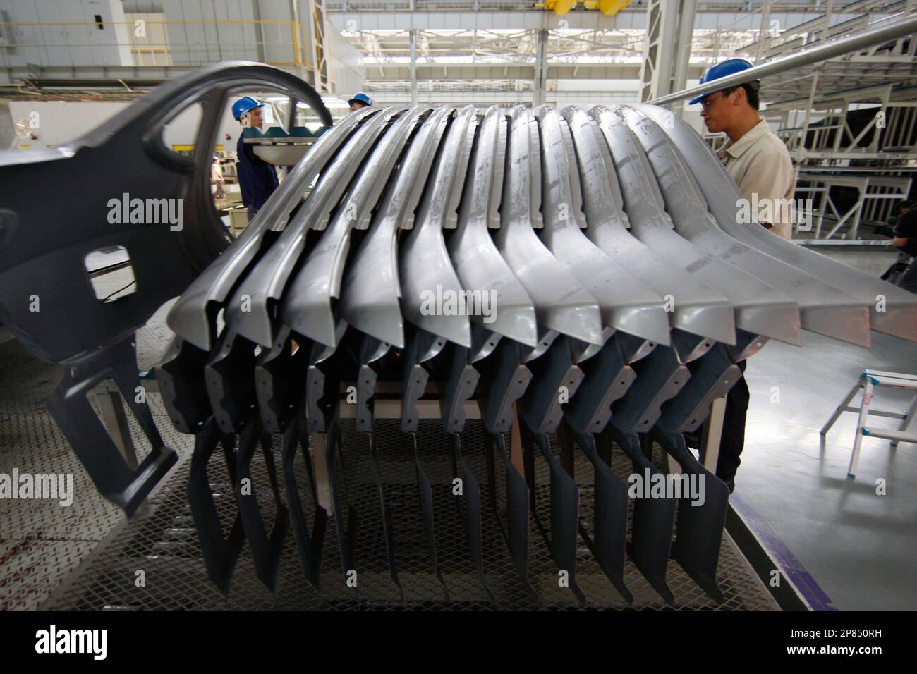 Workers at a Hyundai car factory line up pressed metal parts used in ...