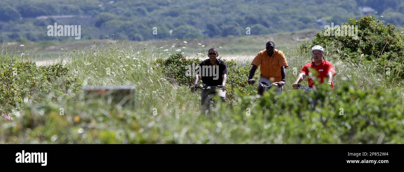President Barack Obama, left, rides his bike with his family and ...