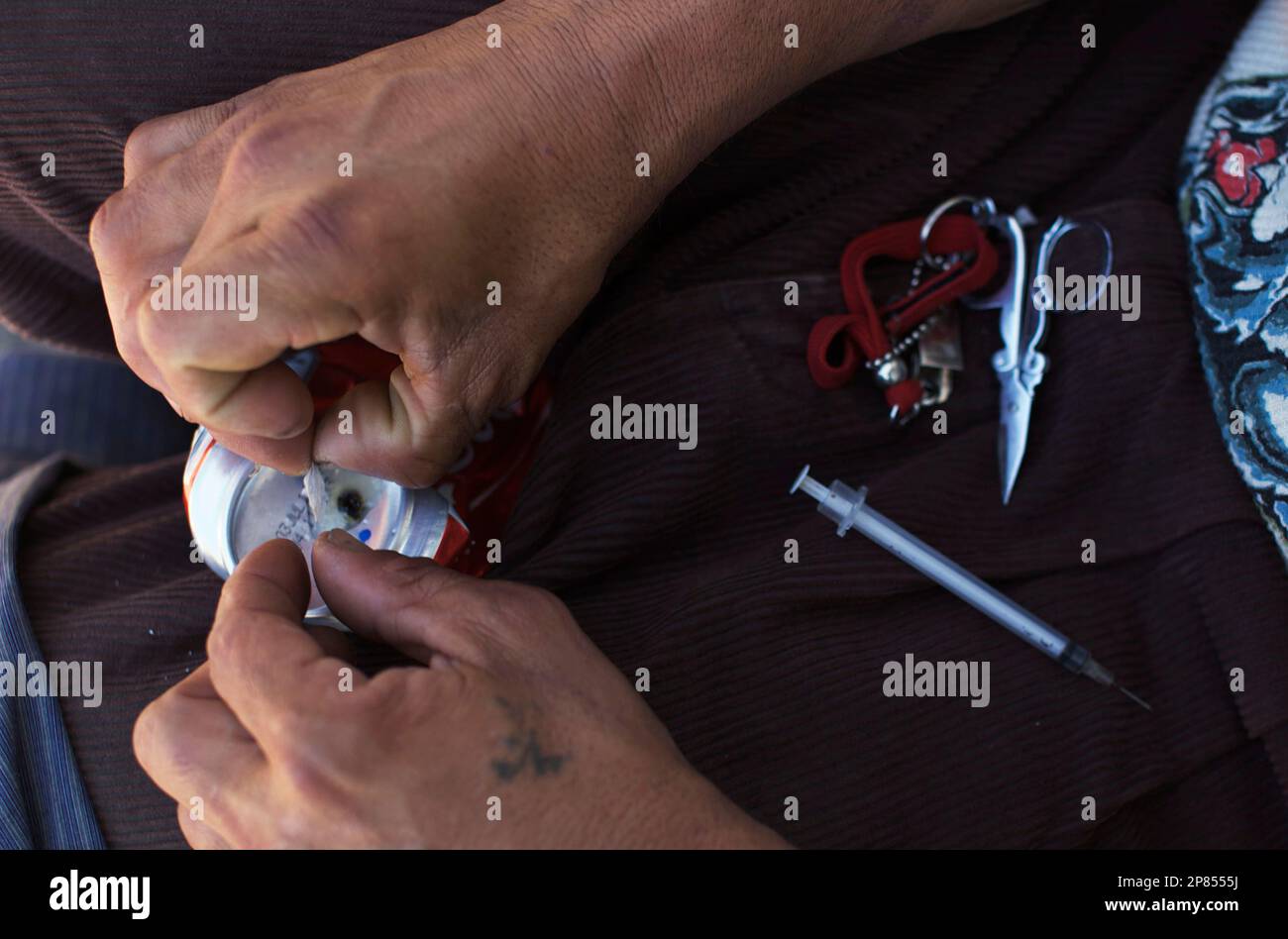 A drug addict prepares his fix of "speedball", a combination of heroin ...