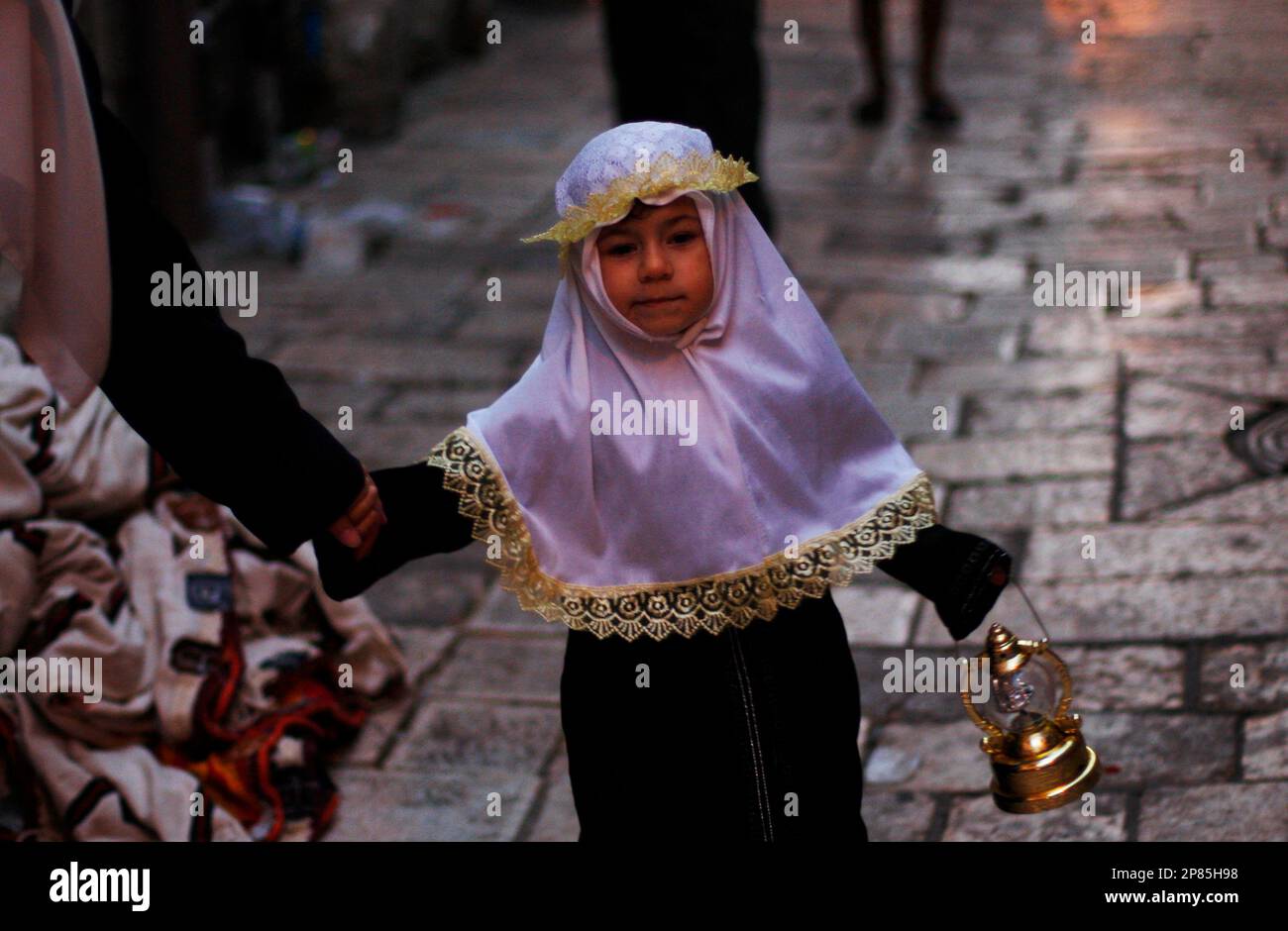 A Palestinian Muslim girls walks with her mother to Al-Aqsa Mosque in ...