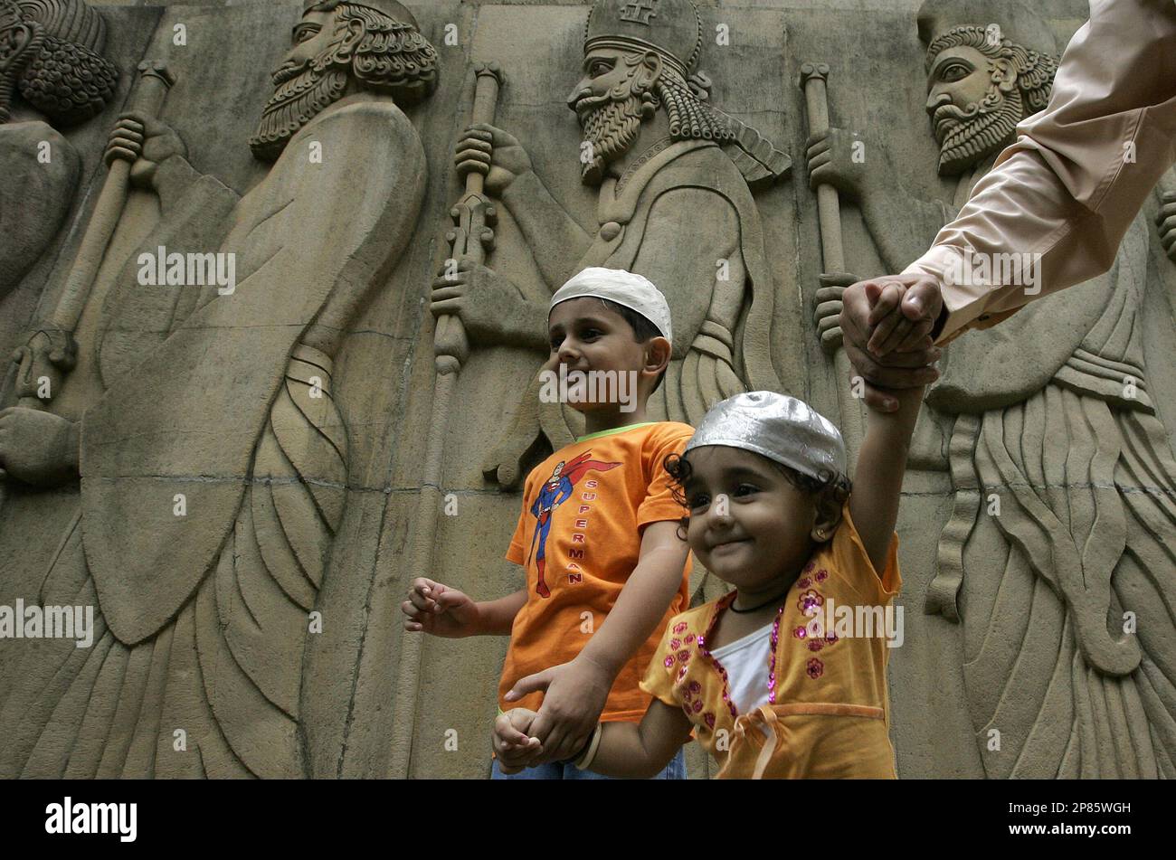Parsi children walk past a bas-relief depicting early Zoroastrians at a ...