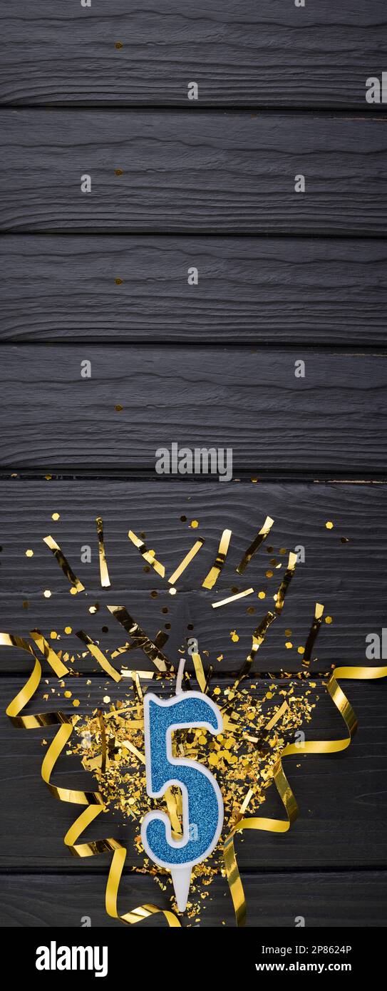 Number 5 blue celebration candle and gold confetti on dark wooden ...