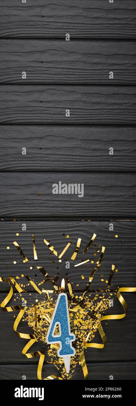 Number 4 blue celebration candle and gold confetti on dark wooden ...