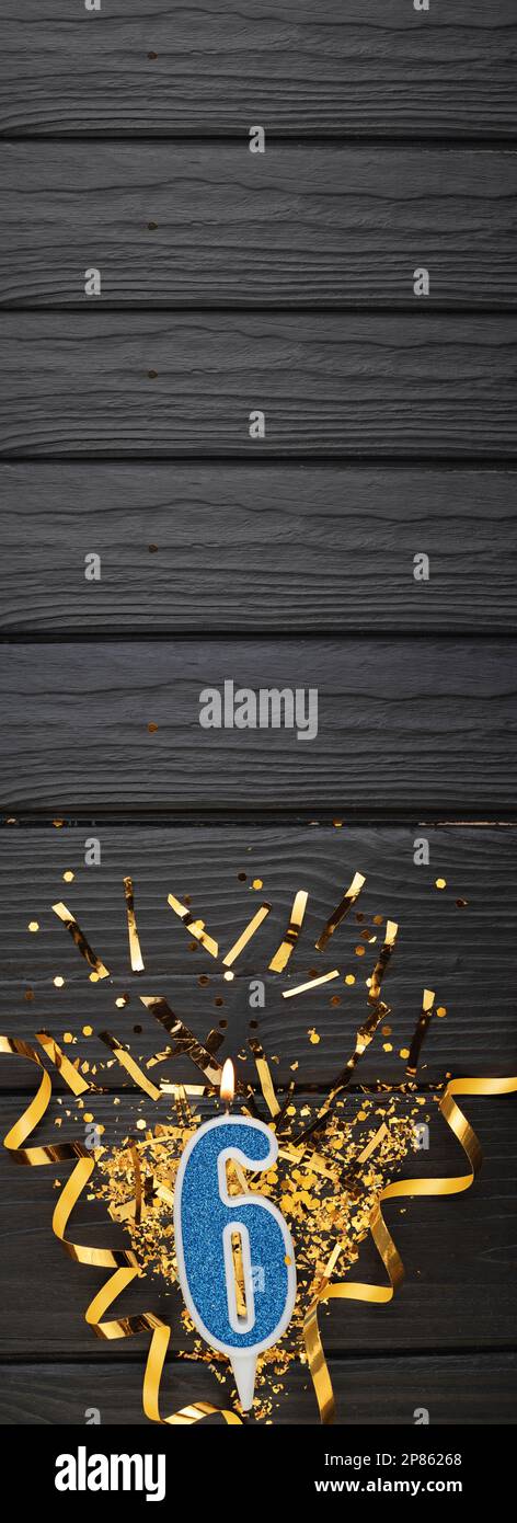 Number 6 blue celebration candle and gold confetti on dark wooden ...