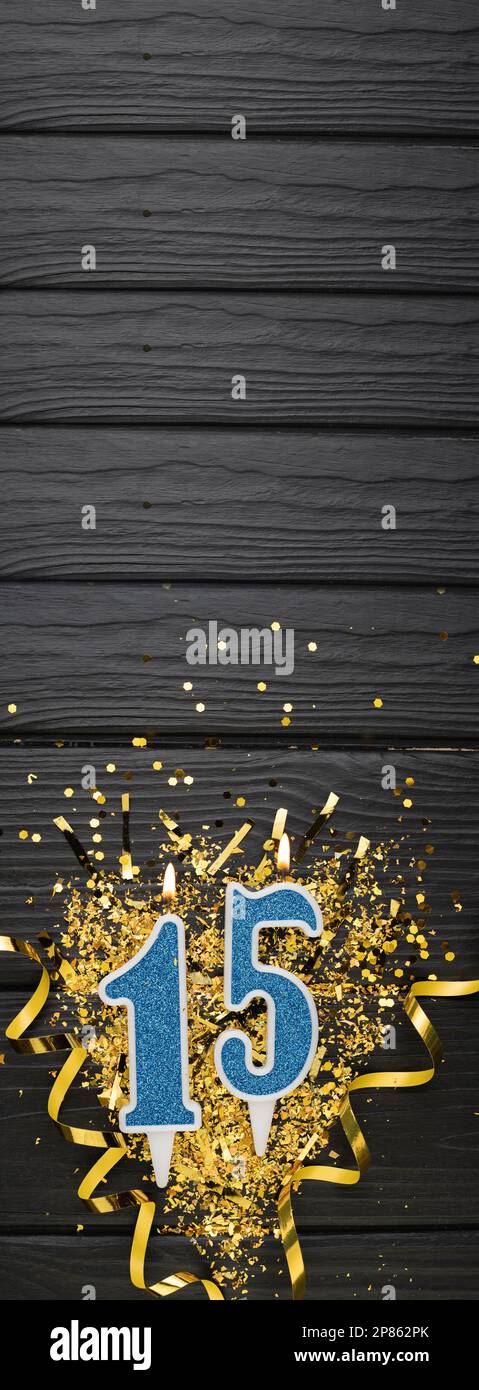 Number 15 blue celebration candle and gold confetti on dark wooden ...