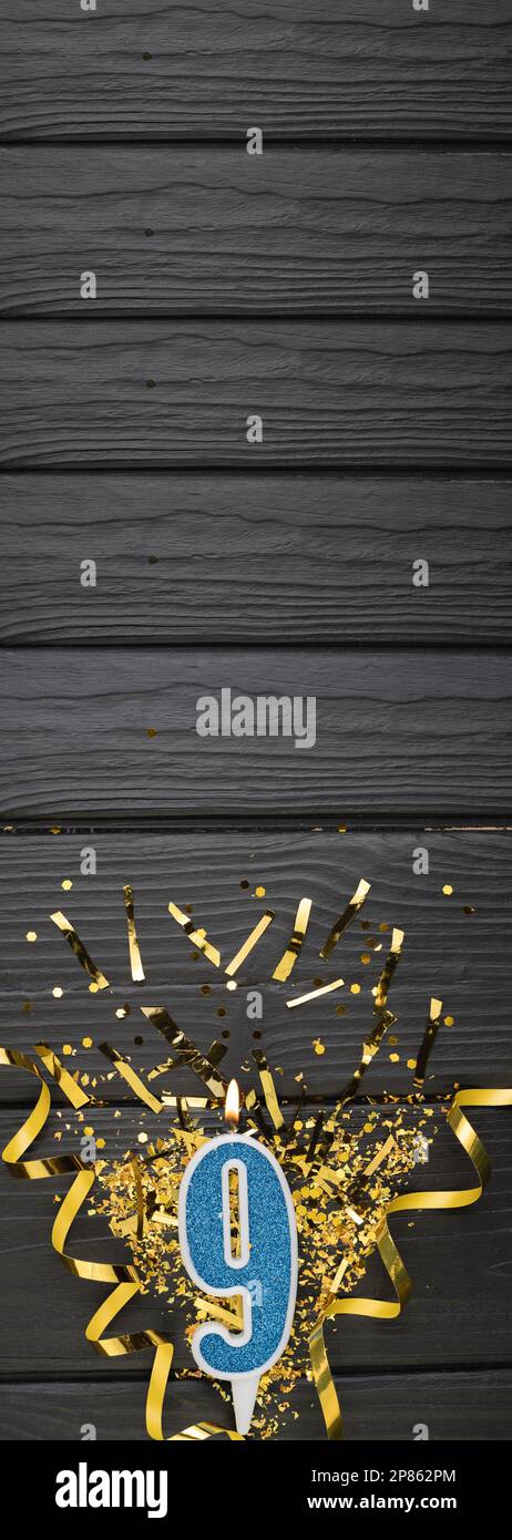 Number 9 blue celebration candle and gold confetti on dark wooden ...