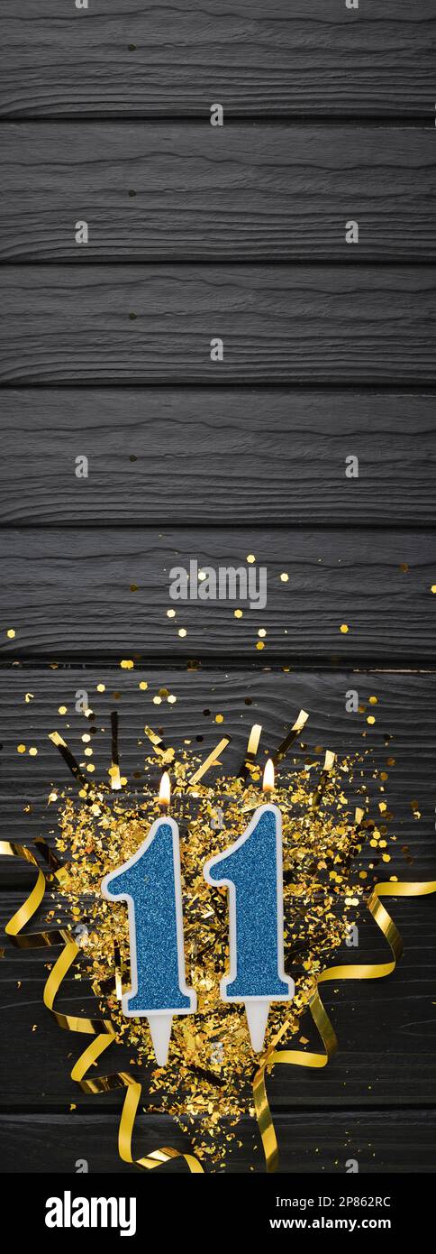 Number 11 blue celebration candle and gold confetti on dark wooden ...