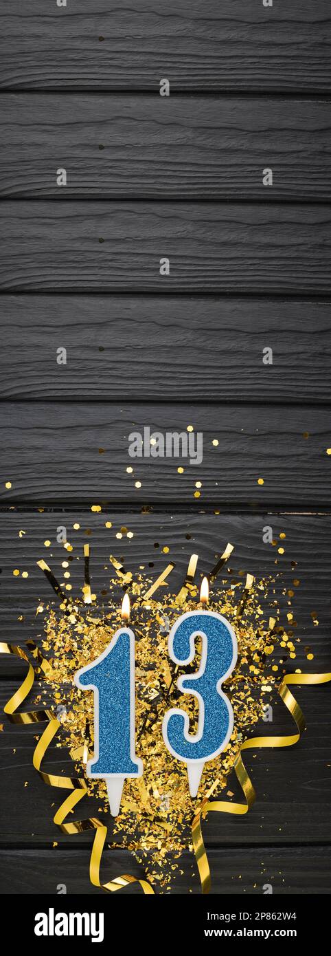 Number 13 blue celebration candle and gold confetti on dark wooden ...
