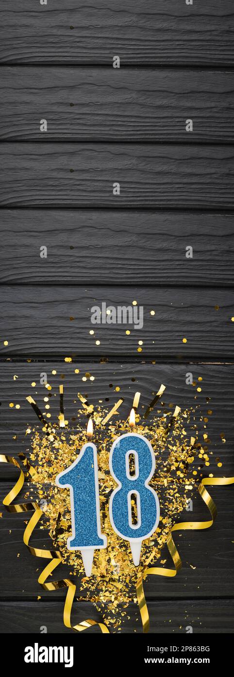 Number 18 blue celebration candle and gold confetti on dark wooden ...
