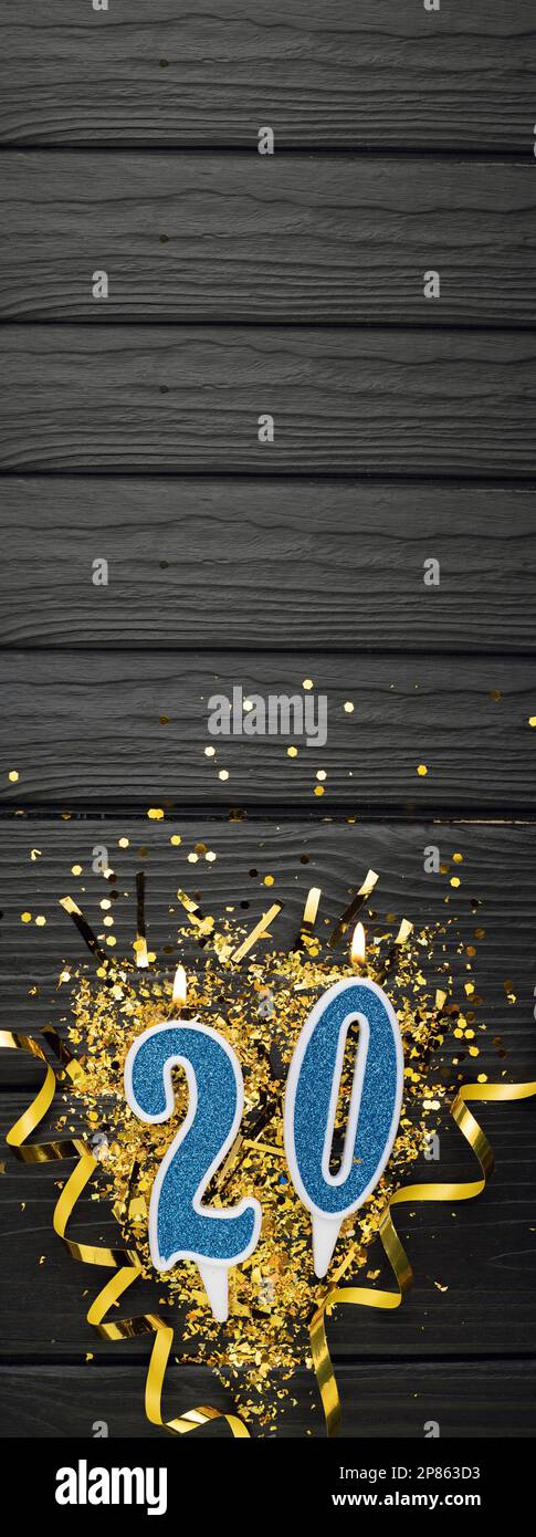 Number 20 blue celebration candle and gold confetti on dark wooden ...